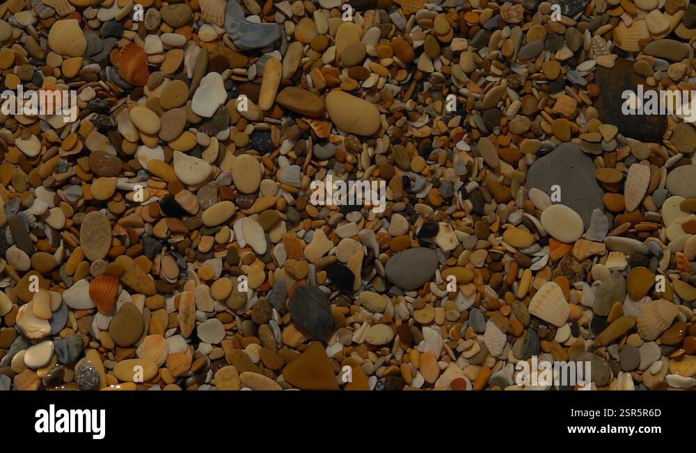 Slow motion of jet waterfall and splash on woman hands on pebble beach ...