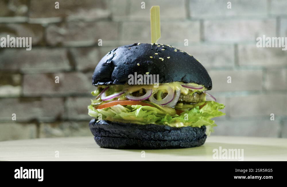 Cooking burger. Close-up of hamburger with black bun, beef or pork ...