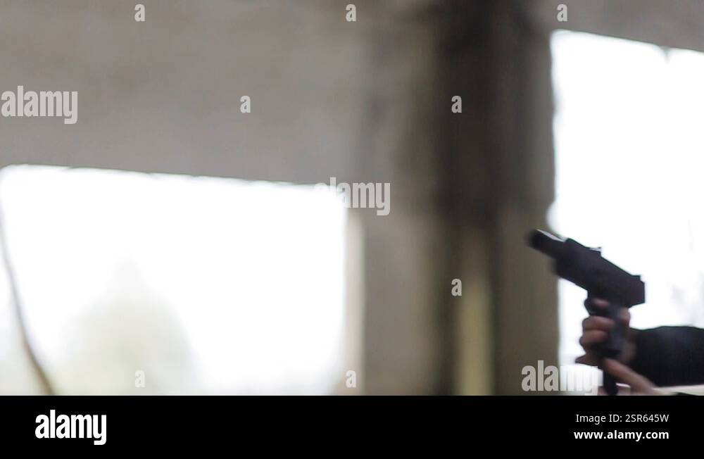 Focused Caucasian boy in black clothes holding gun in hands, looking ...