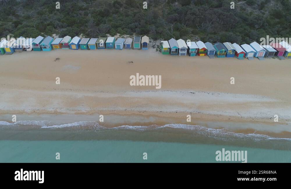 Slow descend with camera tilt over water and iconic beach huts in ...