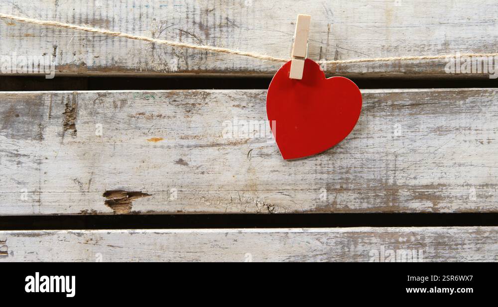 Red heart paper cut pinned on the rope against wooden surface 4k Stock ...