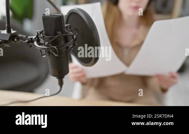 Caucasian woman reading script in radio studio with microphone and pop ...