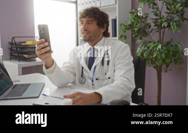 Male doctor engaging in a videoconference in a modern hospital office ...