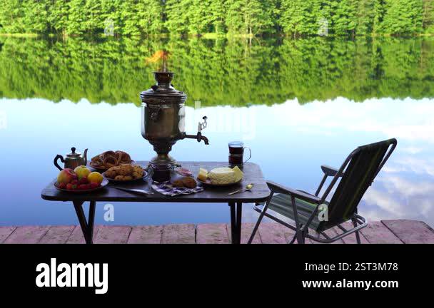 Vintage metal tea samovar with white smoke and food on the table near ...