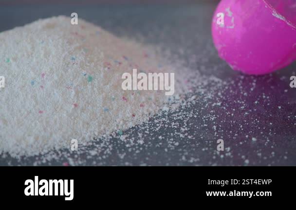 White powder spills from a pink measuring scoop on a surface Stock ...