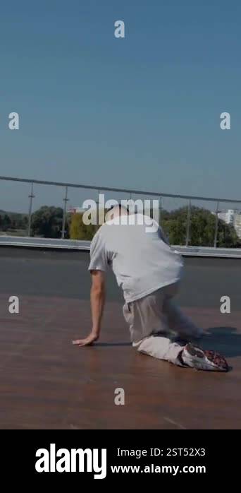 Vertical. The guy coolly dances breakdance on the roof of the house. A ...