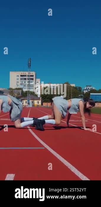 Vertical. Two fiery women joyfully dancing on a stadium track. Women ...