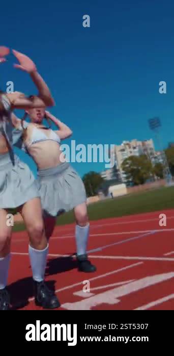 Vertical. Two fiery women joyfully dancing on a stadium track. Women ...