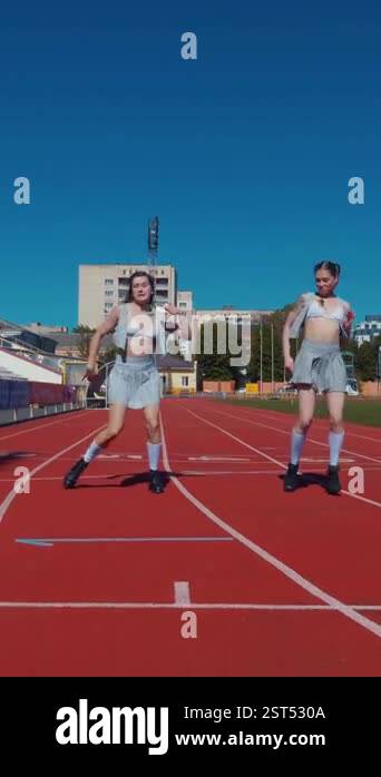 Vertical. Two fiery women joyfully dancing on a stadium track. Women ...