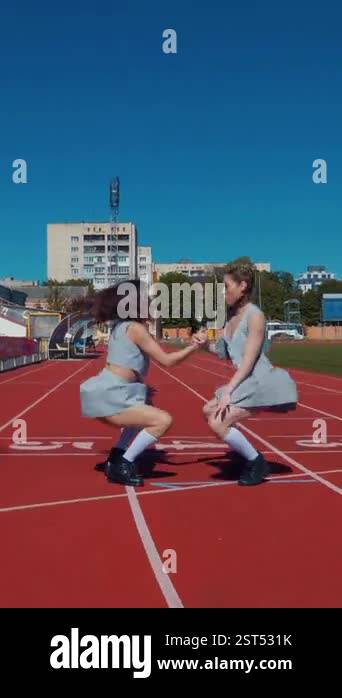 Vertical. Two fiery women joyfully dancing on a stadium track. Women ...