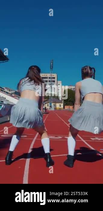 Vertical. Two fiery women joyfully dancing on a stadium track. Women ...