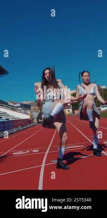 Vertical. Two fiery women joyfully dancing on a stadium track. Women ...