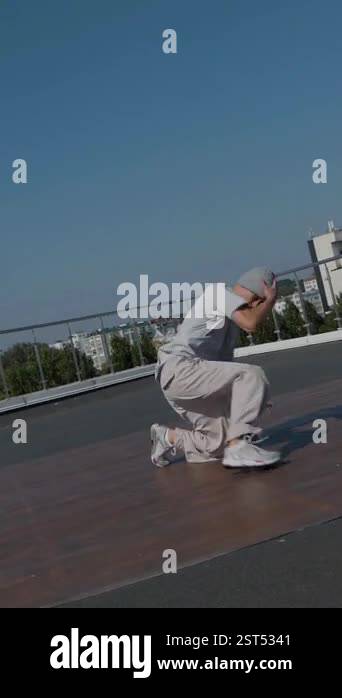 Vertical. The guy coolly dances breakdance on the roof of the house. A ...
