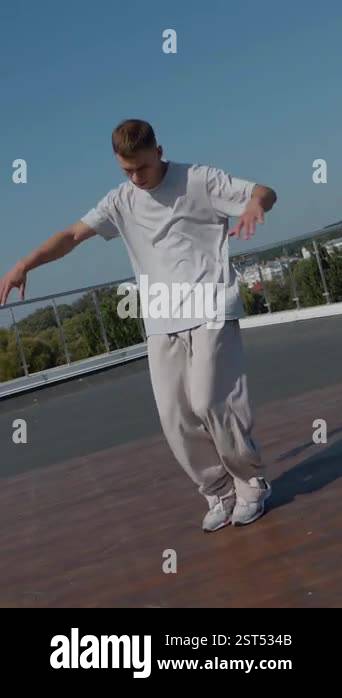 Vertical. The guy coolly dances breakdance on the roof of the house. A ...
