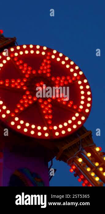 Vertical. A vibrant amusement ride adorned with glowing lights against ...