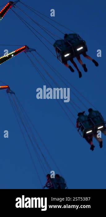 Vertical. A vibrant amusement ride adorned with glowing lights against ...