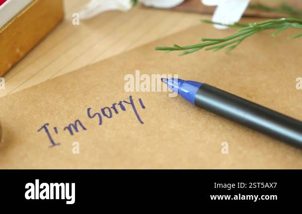 Writing a sincere apology on brown paper with a blue pen and greenery ...