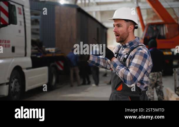 A construction worker uses a walkie-talkie to give instructions while ...