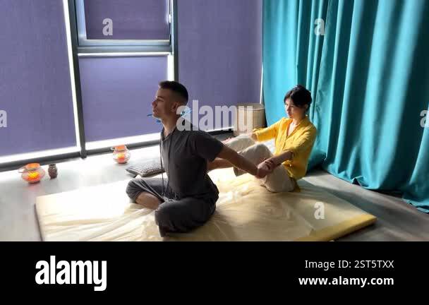 Masseuse making thai yoga massage. Woman therapist doing traditional massage treatment ...