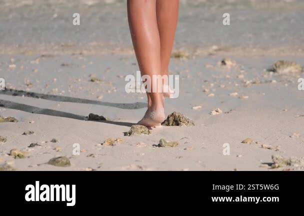 Close up woman legs walking sandy beach, feet leaving imprints on soft ...