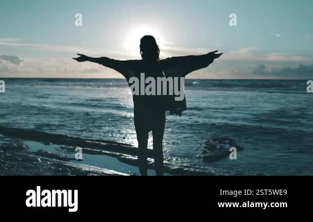 Woman raise hands up on sunset sea beach. Female silhouette stand on ...