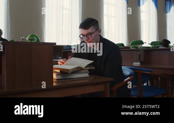A focused student writes notes in a cozy library filled with books and ...