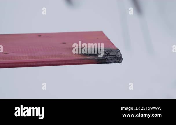 The video shows a closeup of wood affected by fire. A flame bursts ...