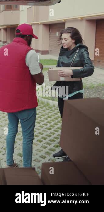 courier African American gives a parce to a woman after signing on ...