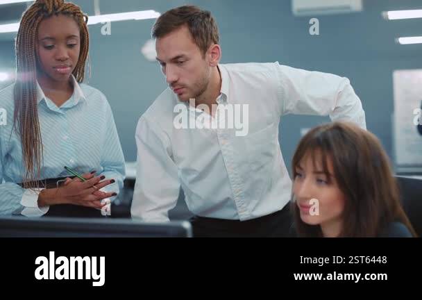 Three multicultural colleagues looking at monitor and discussing report ...