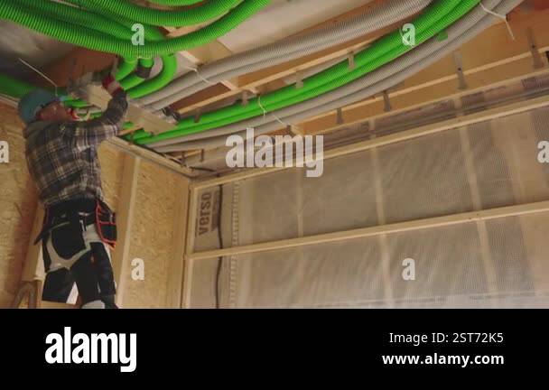 A construction worker is installing air condition duct in the ceiling ...