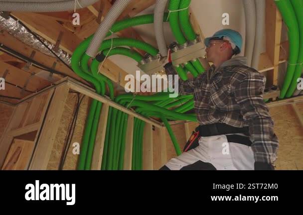 A worker installs air condition duct in a construction area, showcasing ...