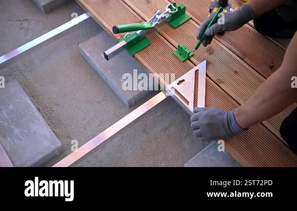 A skilled worker carefully measures and positions wooden planks for ...