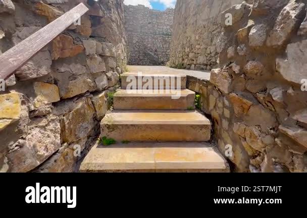 A narrow stone pathway winds through ancient castle ruins, with rugged ...