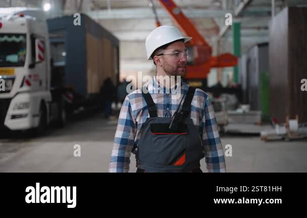 A construction worker in safety gear walks through a modular home ...