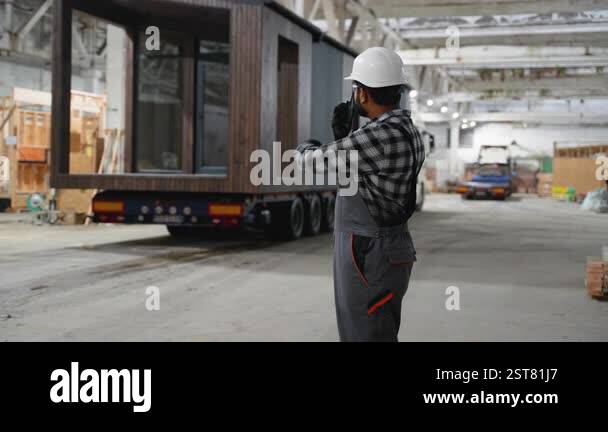 A construction worker communicates via radio while guiding the loading ...