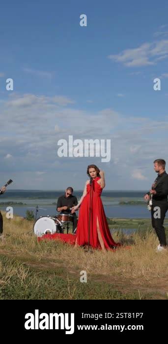 Vertical. A band plays lively outside on a sunny day. Woman sings cool ...