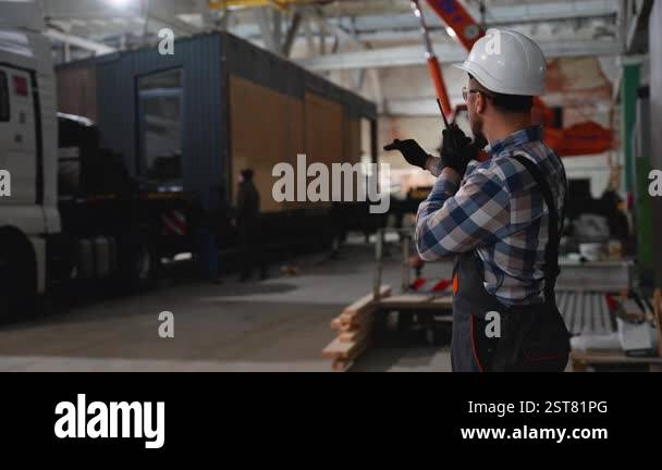 A construction worker uses a walkie-talkie to supervise the loading of ...