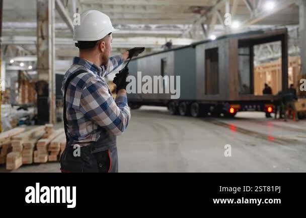 A construction worker uses a radio to coordinate the loading of a ...