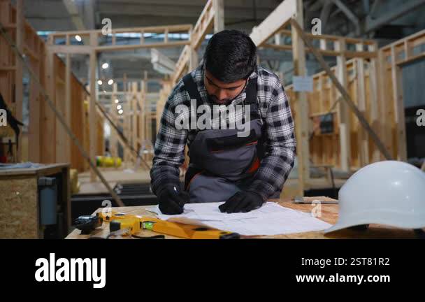 A construction engineer carefully sketches a modular home blueprint at ...