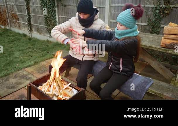 Brother and sister warming hands by fire, enjoying heat from burning ...