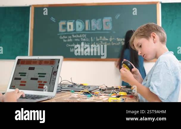 Asian boy coding program while caucasian friend fixing electric board ...