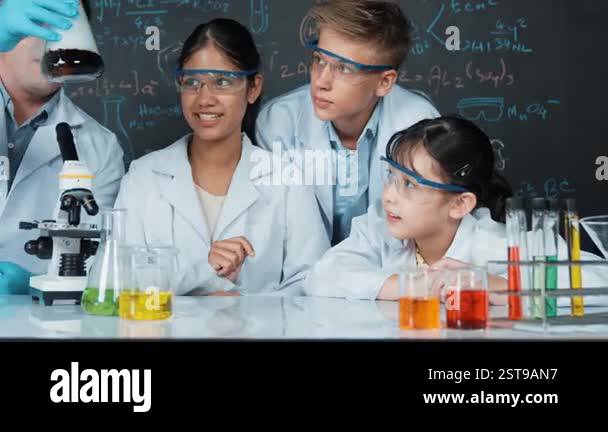 Girl looking at beaker while doing experiment at blackboard with ...