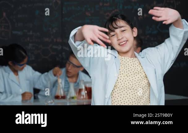 Cute asian scientist waving hand to camera while diverse group doing ...