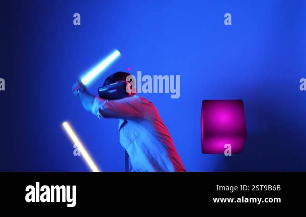 Gamer playing game while holding glowing sword and wearing VR glasses ...