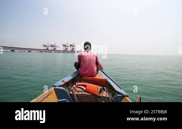 Fisherman Sitting on boat bow sailing forward. Lonely Fisherman on a ...