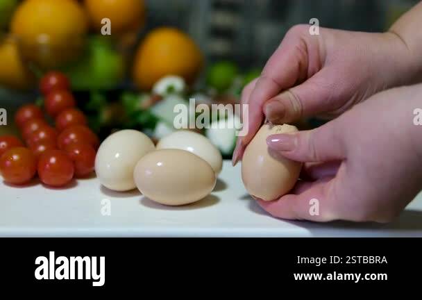 Hands skillfully peel the shells off freshly boiled eggs, revealing the ...