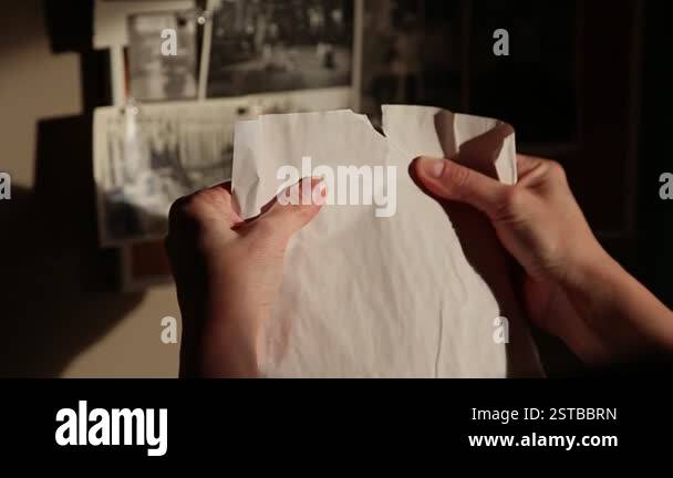 A pair of hands forcefully ripping a piece of paper, revealing jagged ...