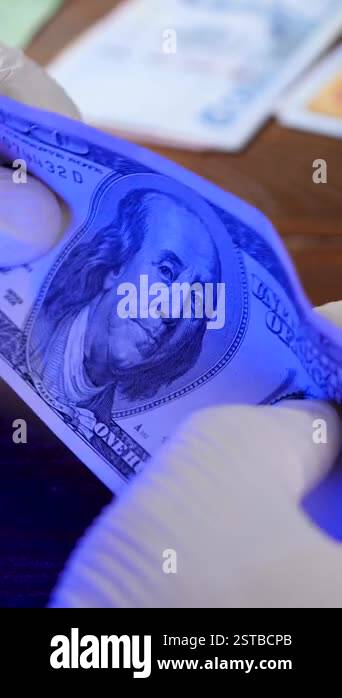 Inspection of banknote for counterfeit money. 100 American dollars bill ...