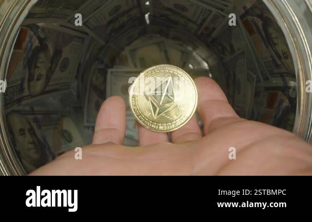 Close-Up View of a Hand Dropping a Gold Ethereum Coin Into a Glass Jar ...