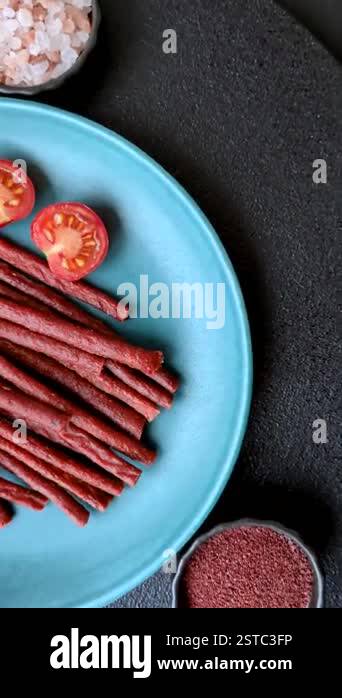 Jerky dried fish sticks with salt and spices on a dark concrete ...